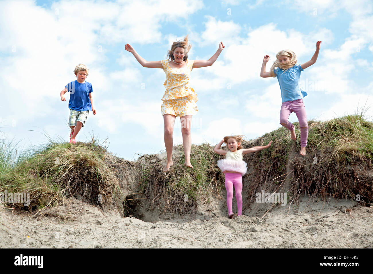 Mother with three children jumping off dunes, Wales, UK Stock Photo - Alamy
