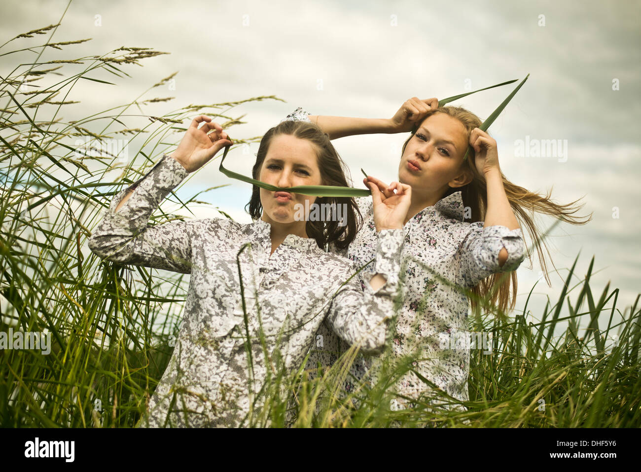 Two young women making faces with grass Stock Photo - Alamy