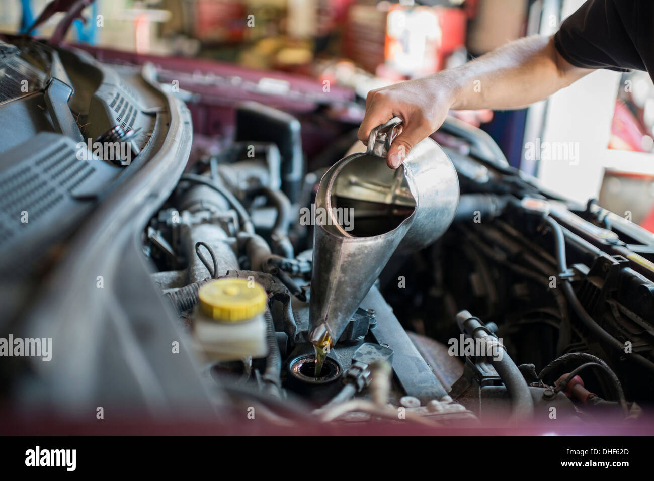 Mechanic pouring liquid into car Stock Photo - Alamy