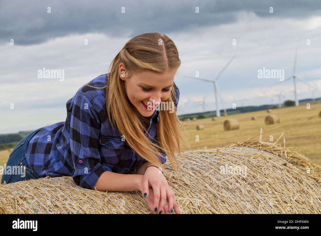 Portrait of young woman leaning over straw bale Stock Photo - Alamy