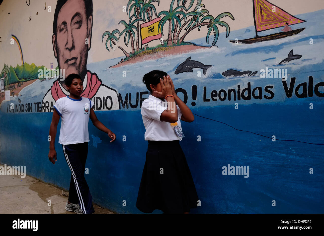 Schoolgirls from the Guna people walk past a painted wall depicting ...