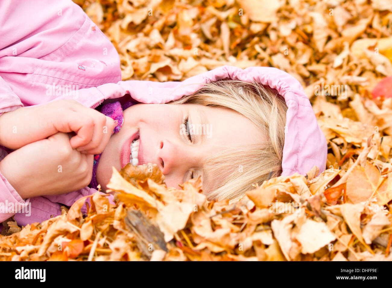Little Girl Lying in Autumn Leaves with a big grin Stock Photo - Alamy