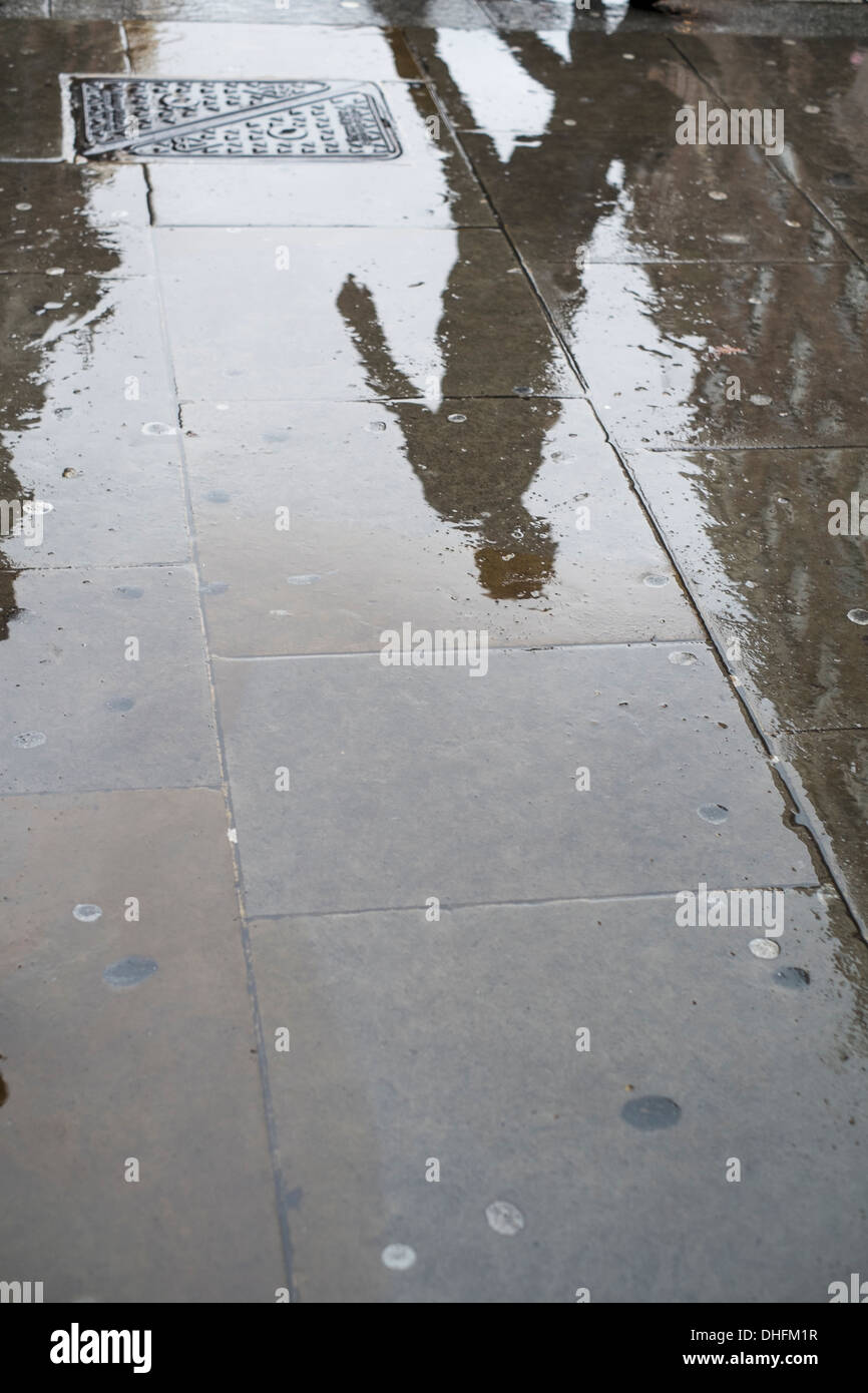 Reflection of a pedestrian projected on wet pavement Stock Photo - Alamy