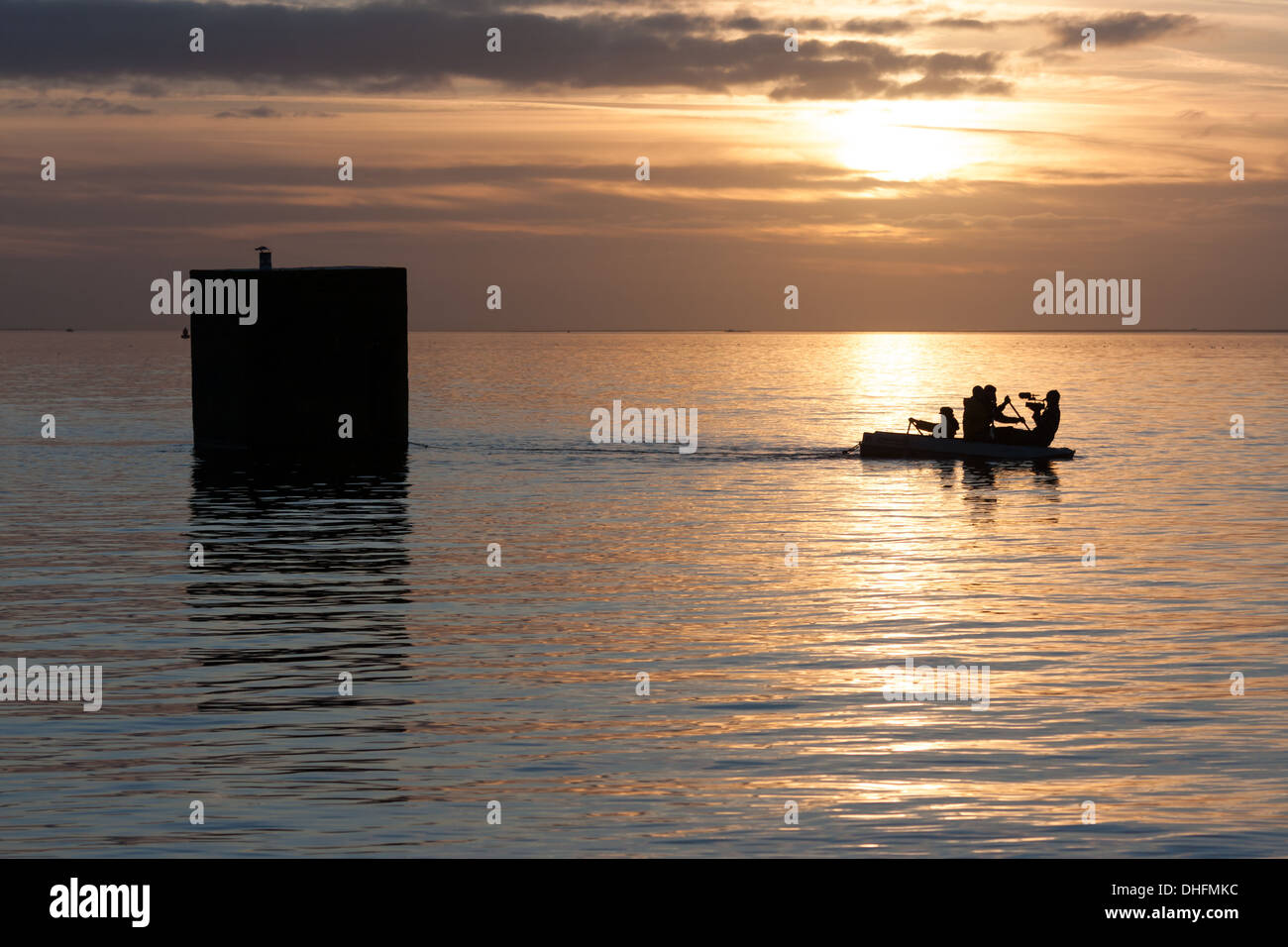 Man rowing with a floating cube in a beautiful sunset Stock Photo - Alamy