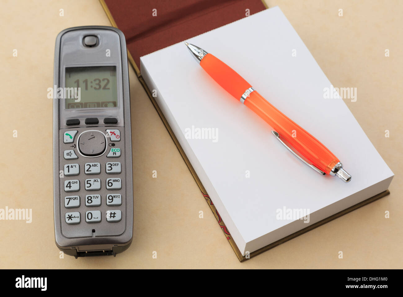 Cordless modern digital telephone handset with a blank notepad notebook ...