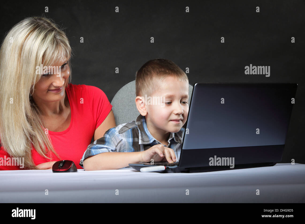 mother with son together looking on the laptop computer black ...