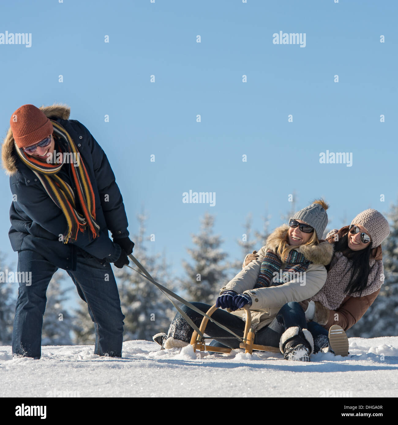 Friends having fun on snow sledge sunny wintertime Stock Photo - Alamy
