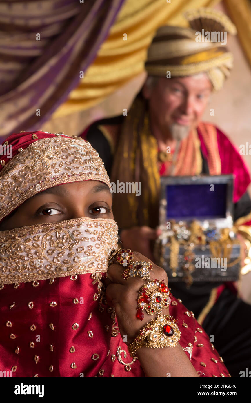 Oriental princess with silk veil and in the background a genie bringing ...