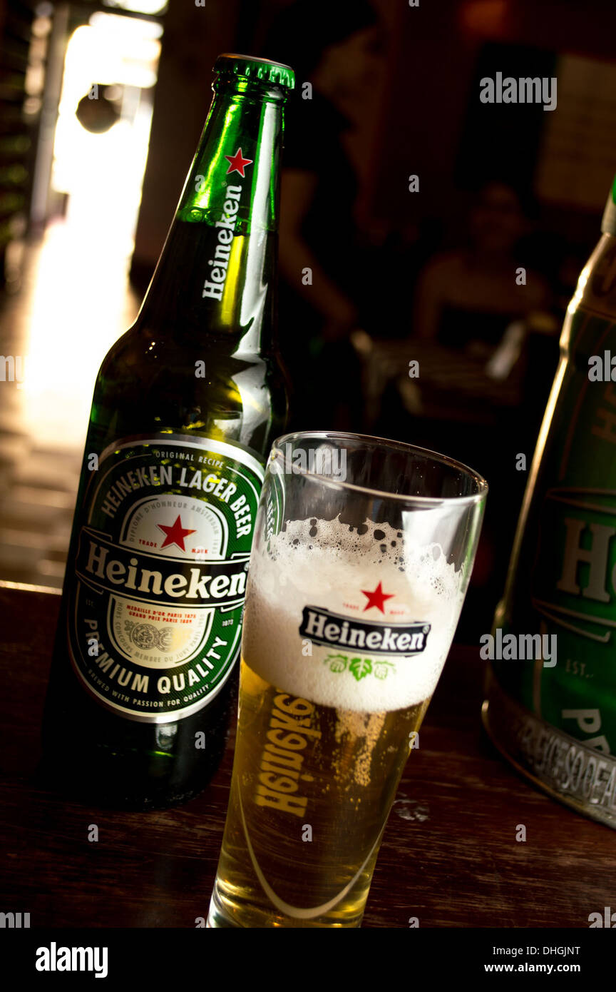 A glass of Heineken beer, with a bottle of the same brand, served in a ...