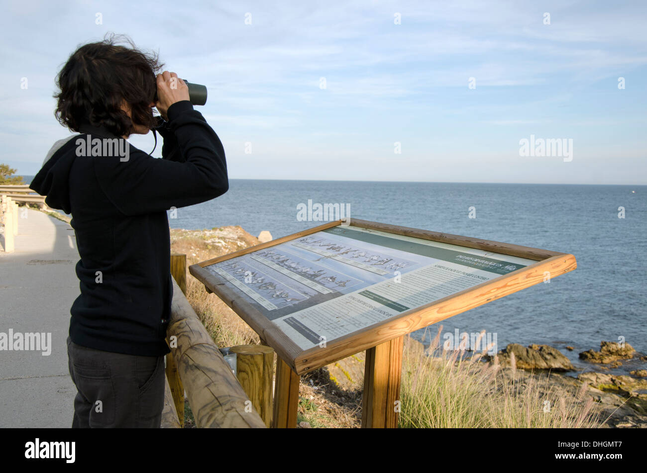 Woman, birdwatching, in front of board showing bird species for ...