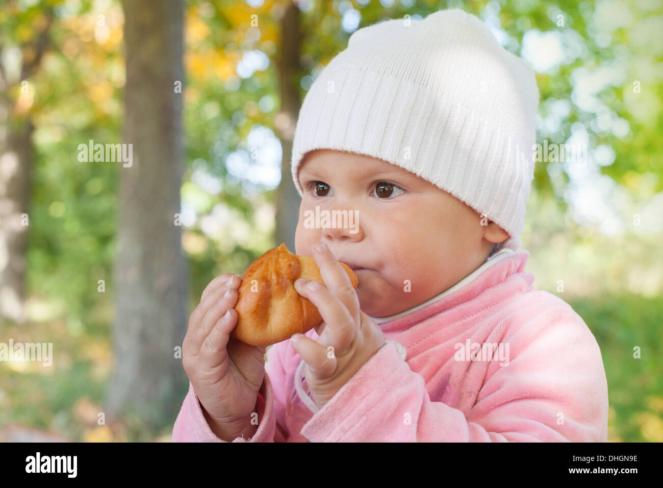 Little Caucasian baby girl in autumn park eats small pie Stock Photo ...
