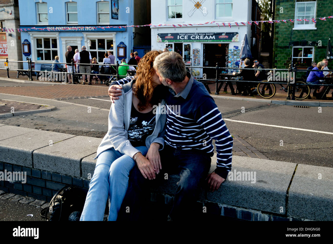 Couple sitting on wall kissing Stock Photo - Alamy