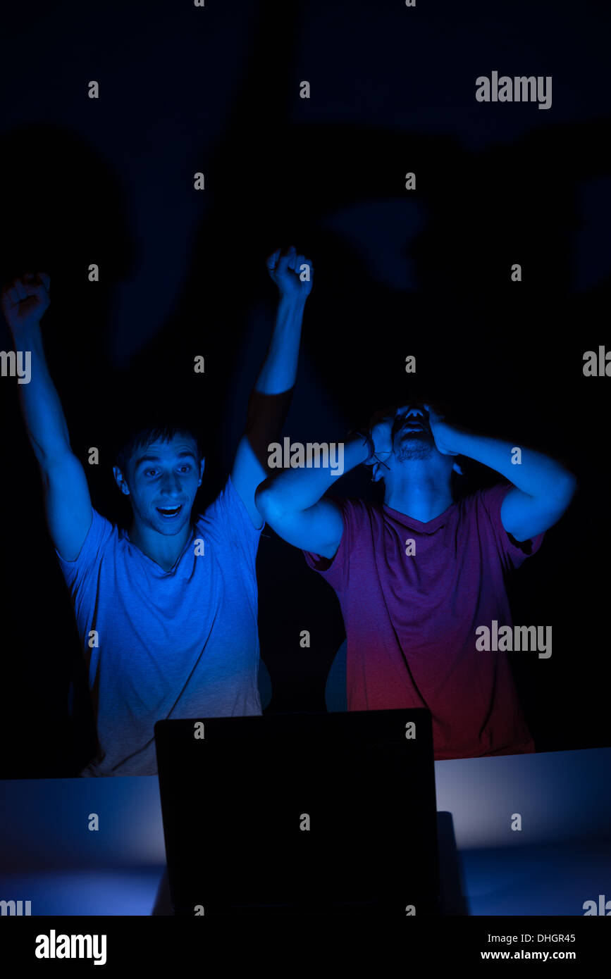 Two guys in front of a computer screen getting all excited about ...