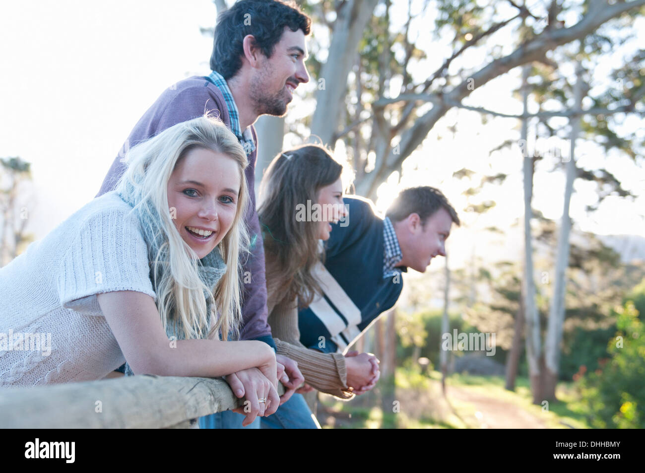 Group of four friends leaning on fence Stock Photo - Alamy