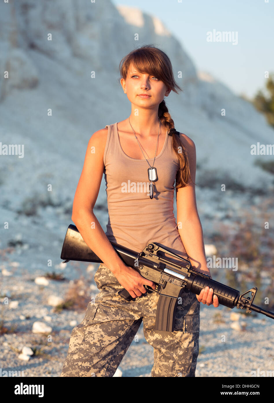 Young beautiful female soldier dressed in a camouflage with a gun in ...