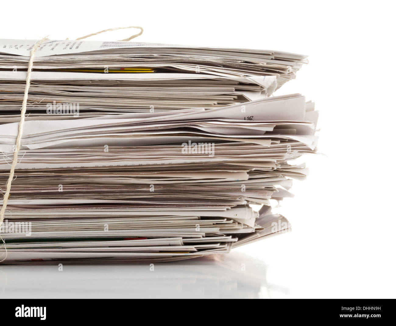 Tied up stack of old newspapers collected for recycling on white ...