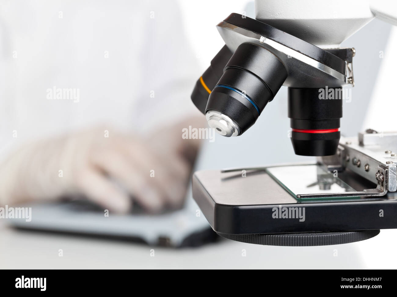 Researcher working on laptop behind microscope Stock Photo - Alamy