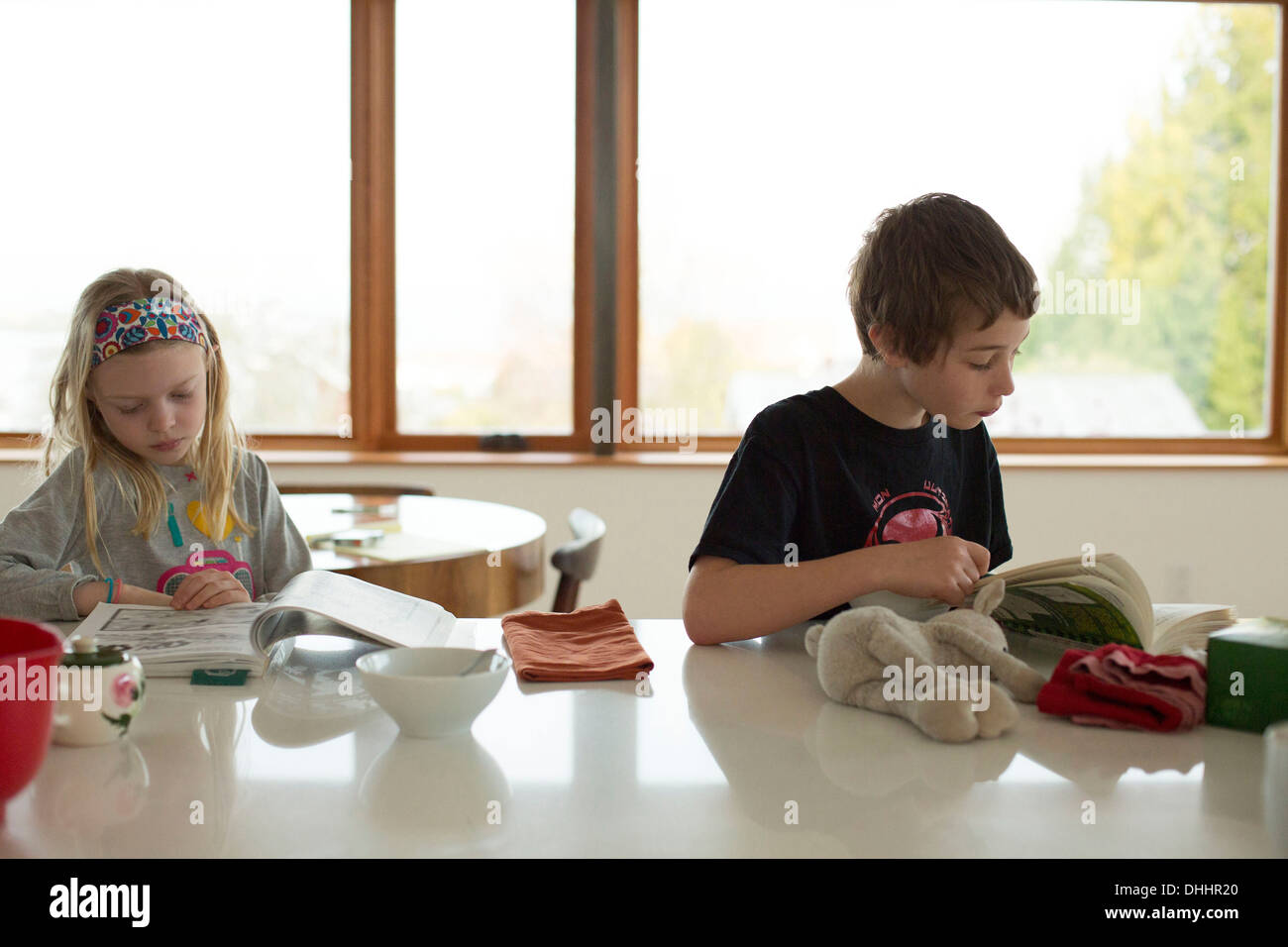 Boy and girl sitting at table reading Stock Photo - Alamy