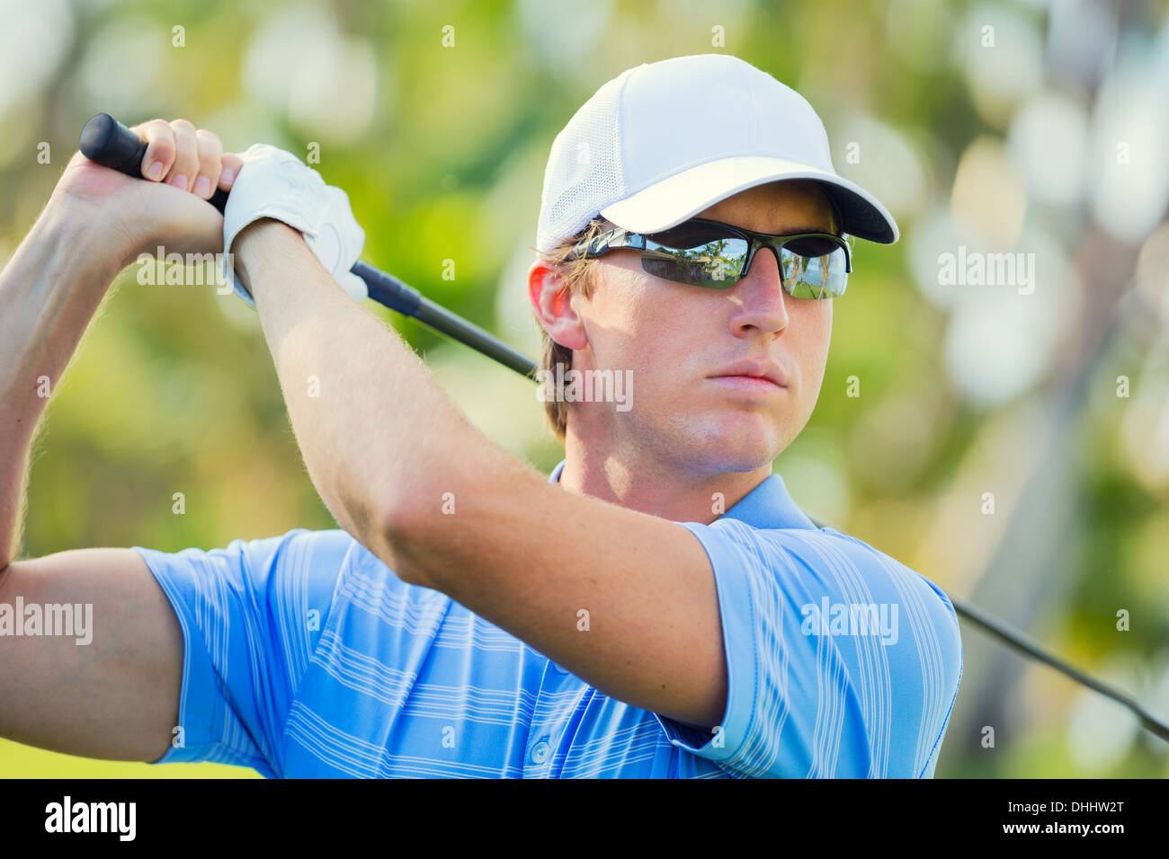 Young man swinging golf club Stock Photo - Alamy