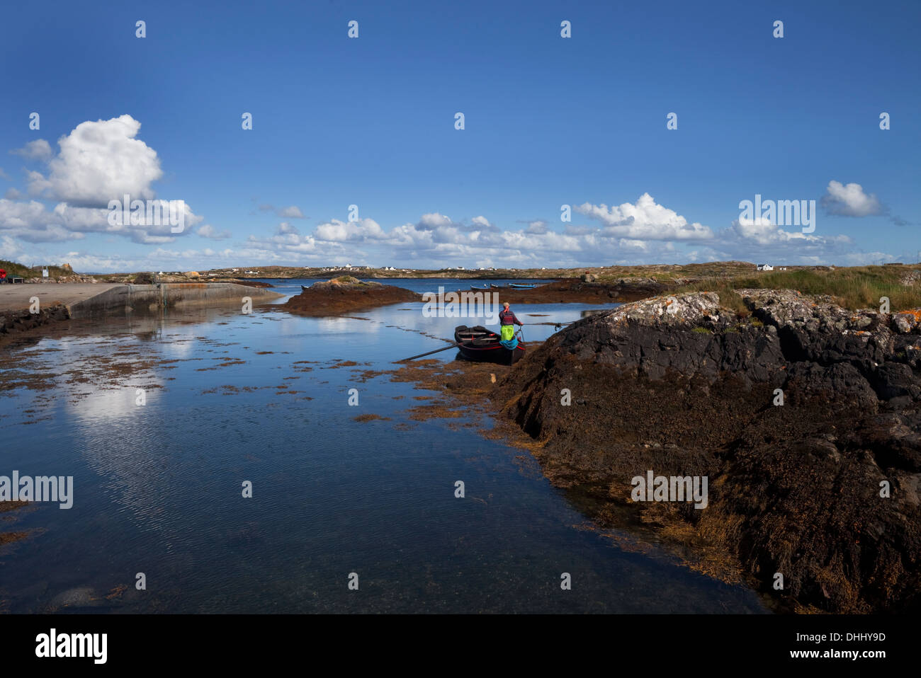Old fisherman in his traditional currach, moored in a sea inlet on ...