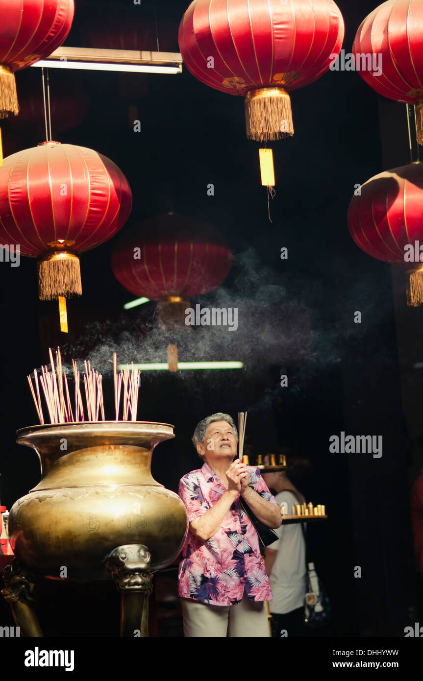 An old woman praying and offering joss stick in a Chinese temple Stock ...