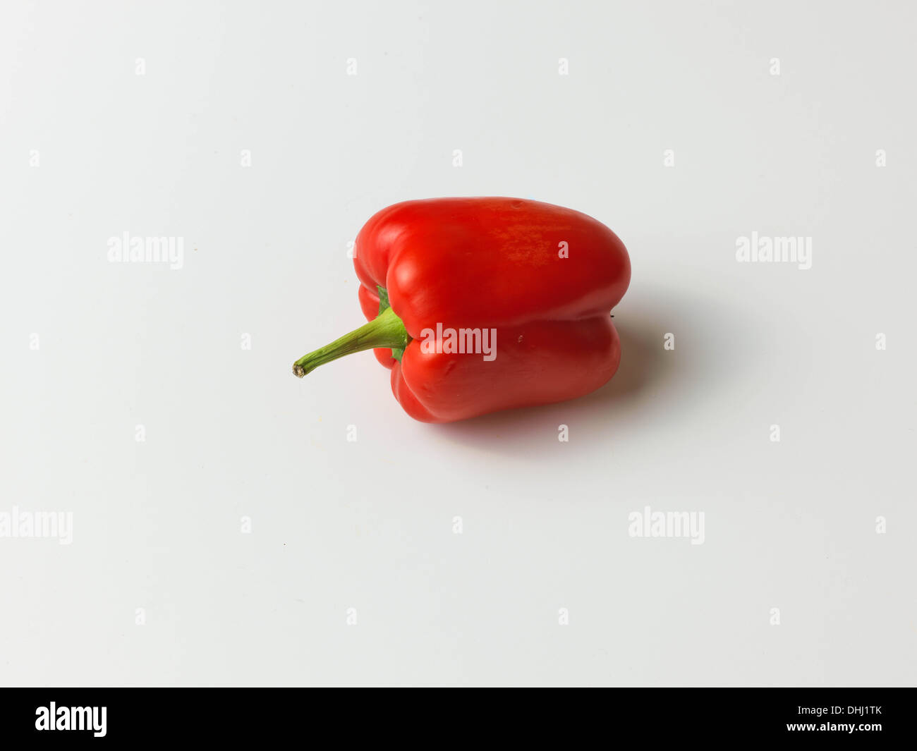 A pepper lying down against a white background with a shadow to the ...