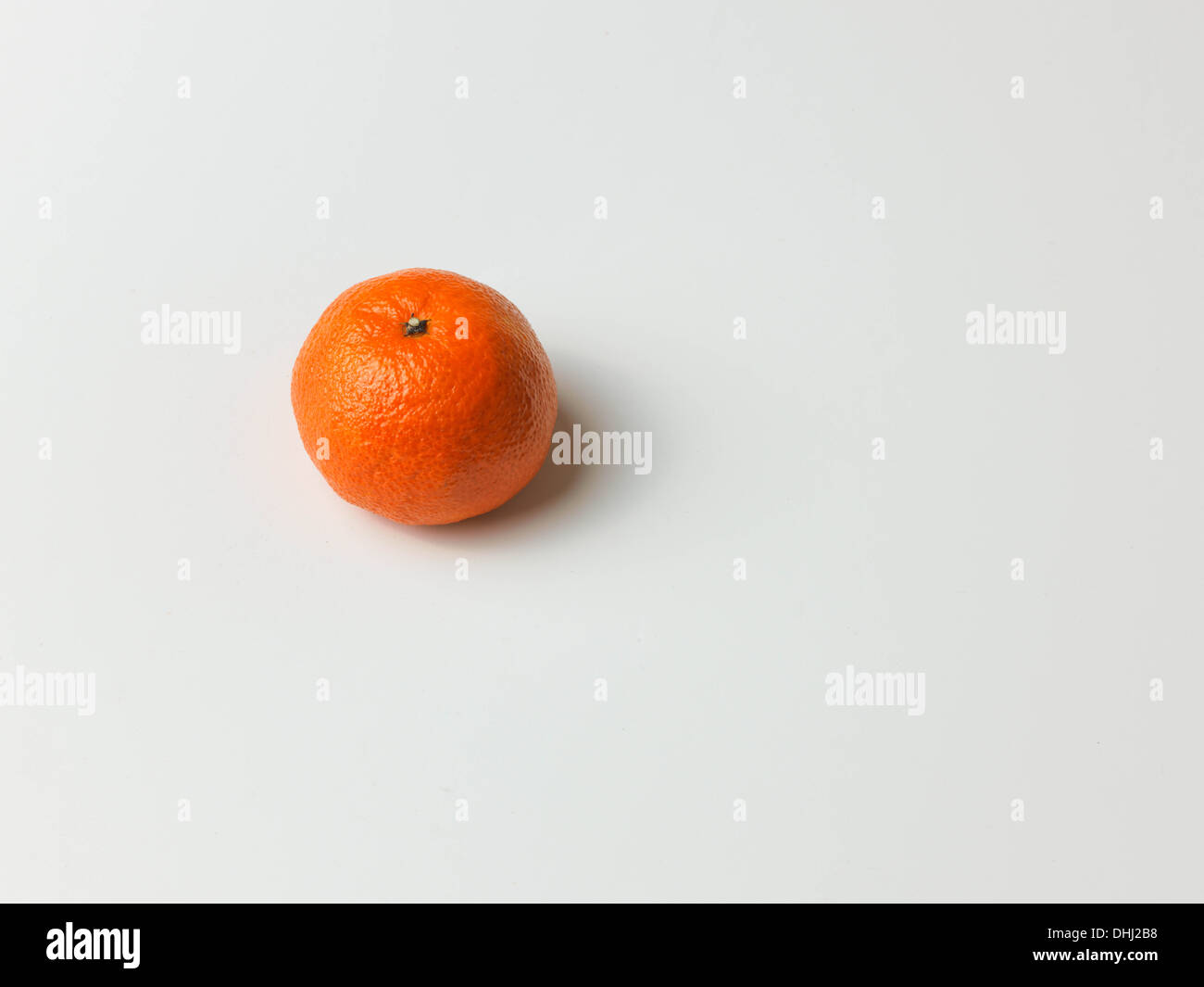 A single orange Clementine sits on a white background with a shadow to ...