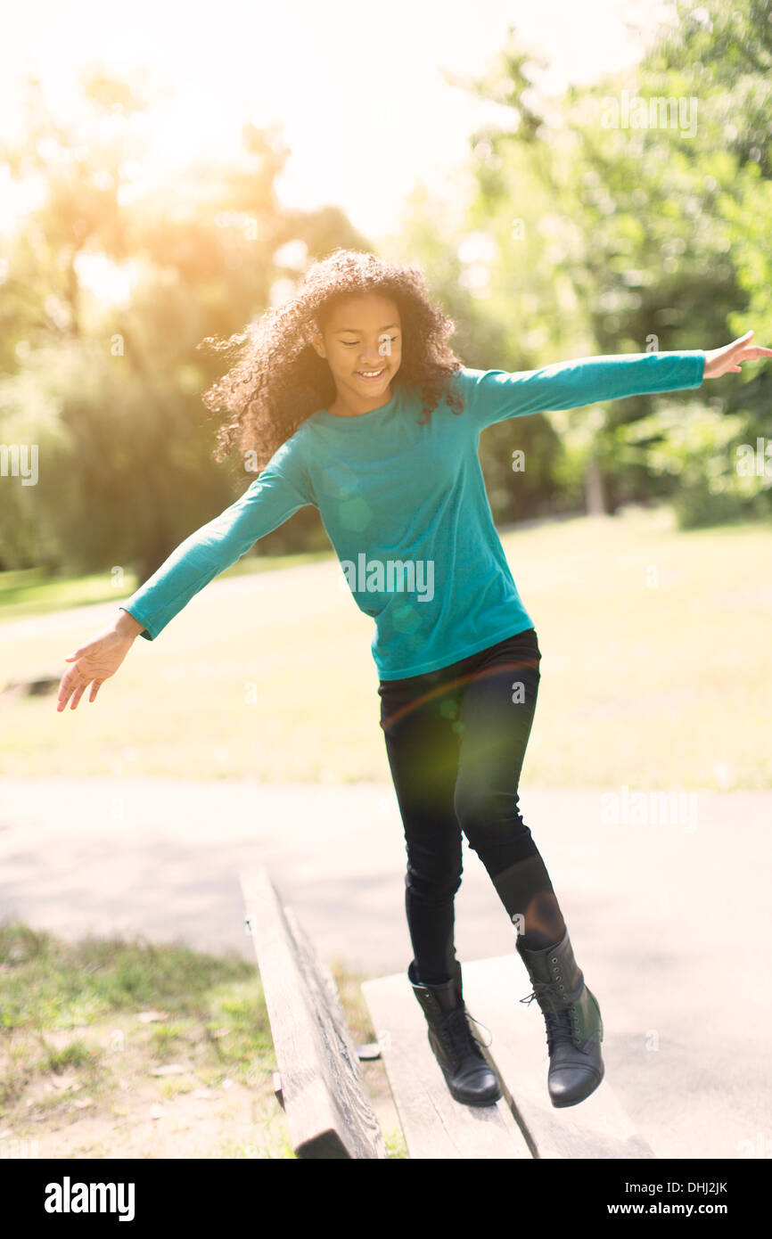 Young girl balancing on bench in park Stock Photo - Alamy