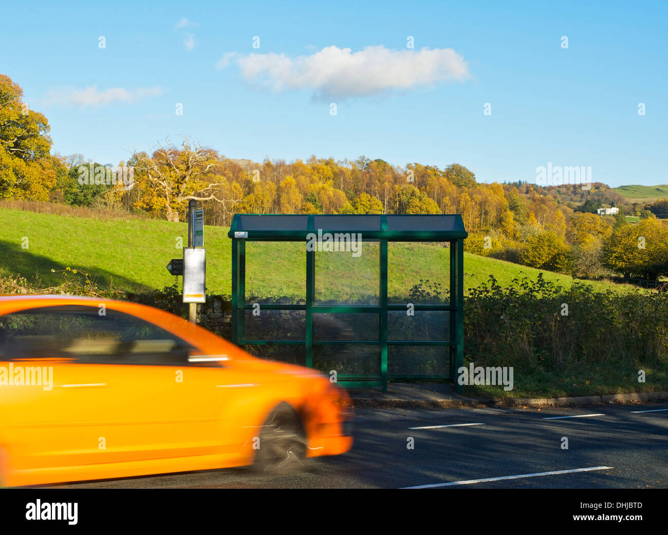 Car passing a bus stop on the A591, near Ambleside, Lake District ...