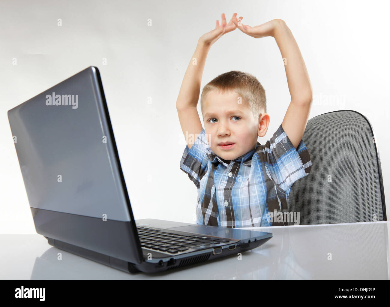 Triumphing child boy with a laptop notebook computer on white ...