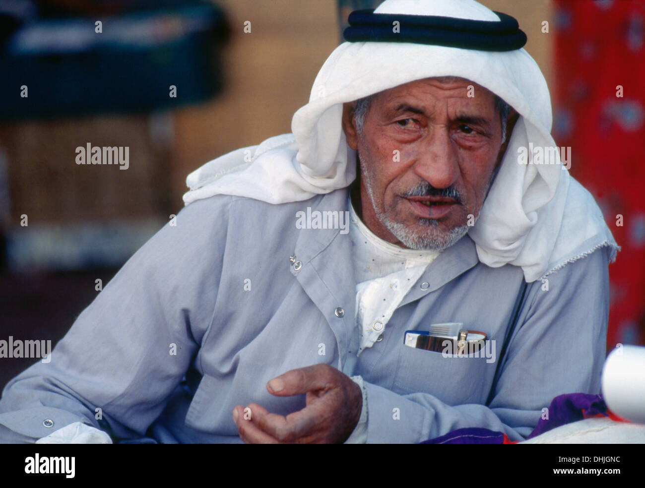 An Arab man in rural Syria wearing a kaffiyeh leans against a pillow ...