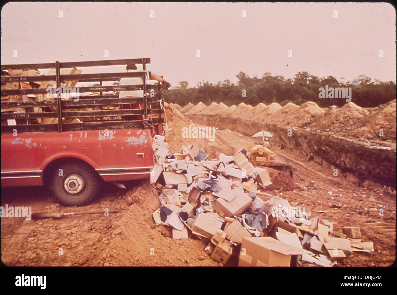 Solid waste is shown being disposed of in trenches at a sanitary ...