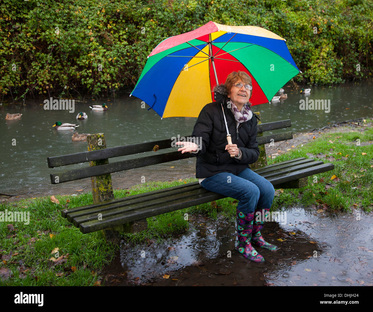 Lady sitting in rain under umbrella Stock Photo - Alamy