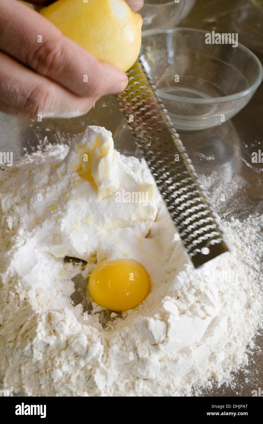 Grating lemon into pastry, together with flour and egg, baking ...
