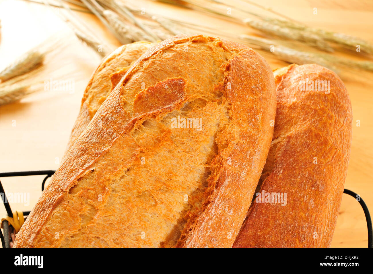 closeup of some demi baguettes or bread rolls in a basket, with wheat ...