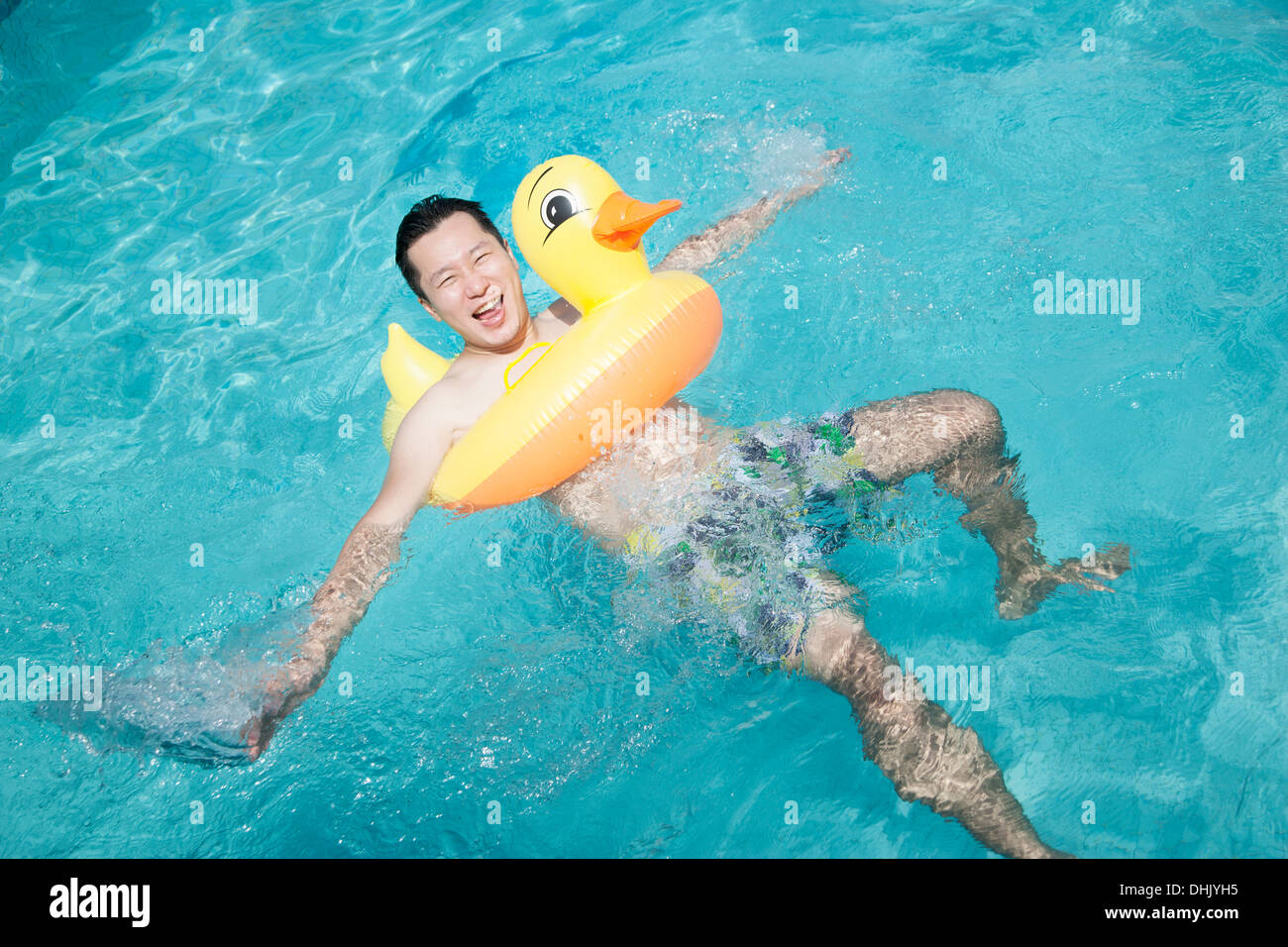 Man wearing a yellow duck inflatable tube and playing in the pool Stock ...