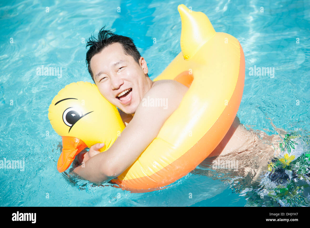 Man wearing a yellow duck inflatable tube and playing in the pool Stock ...