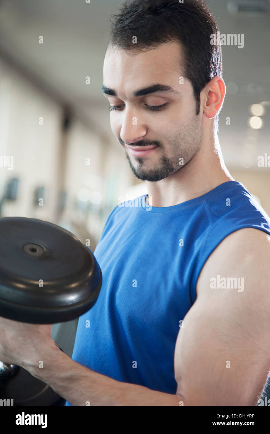 Portrait of young muscular man lifting weights in the gym Stock Photo ...
