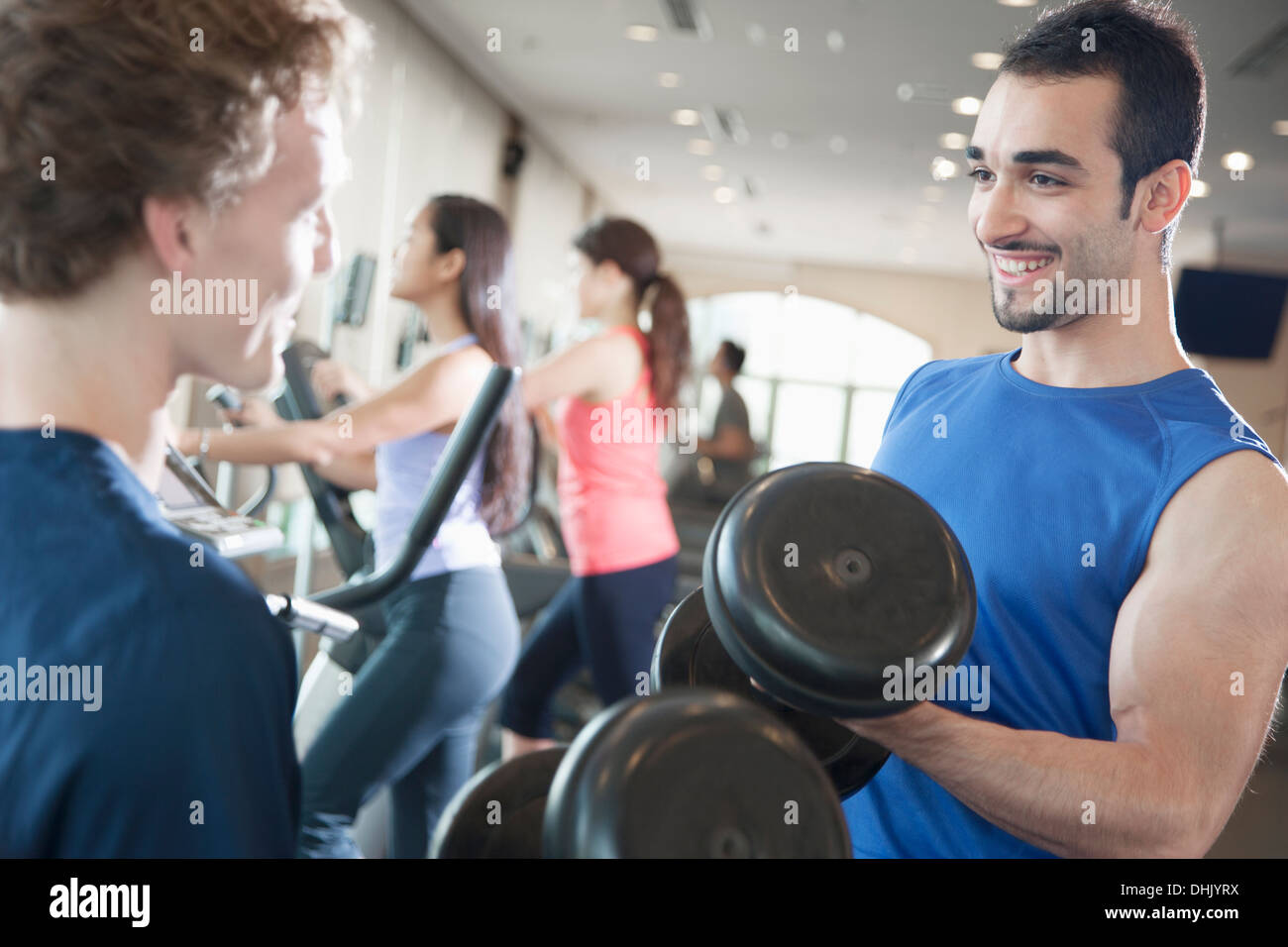 Two young men smiling and lifting weights in the gym Stock Photo - Alamy