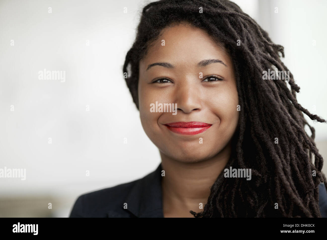 Portrait of smiling businesswoman with dreadlocks, head and shoulders ...