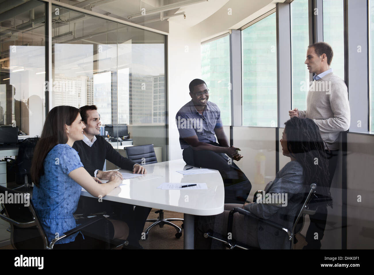 Five business people sitting at a conference table and discussing ...
