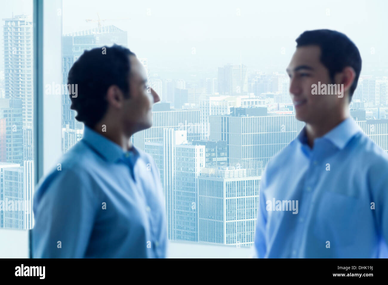 Two businessmen standing by the window and talking in the office Stock ...