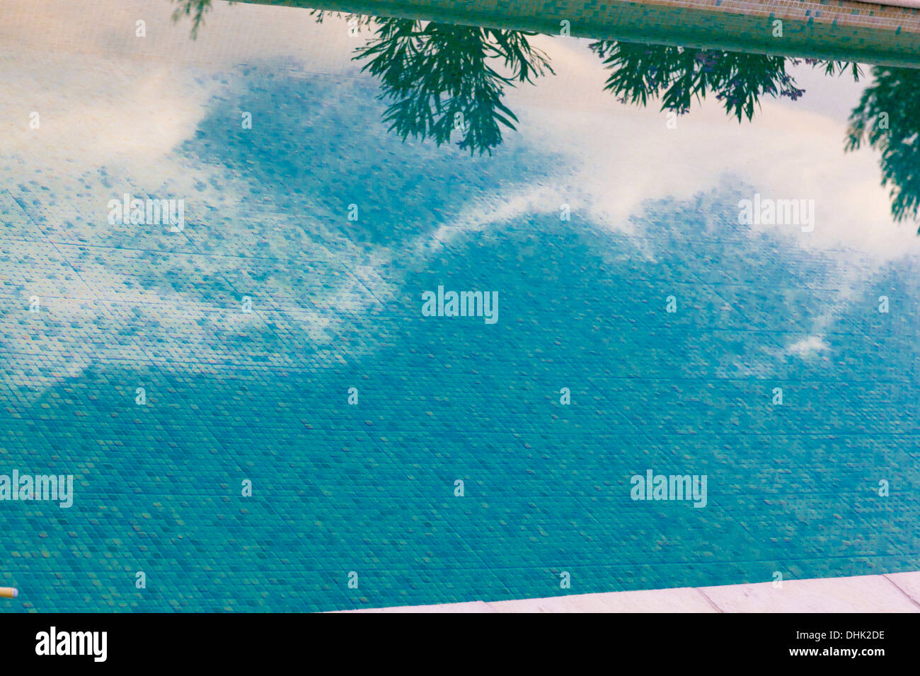 Clouds and sky reflected in a blue tiled swimming pool in the south of ...