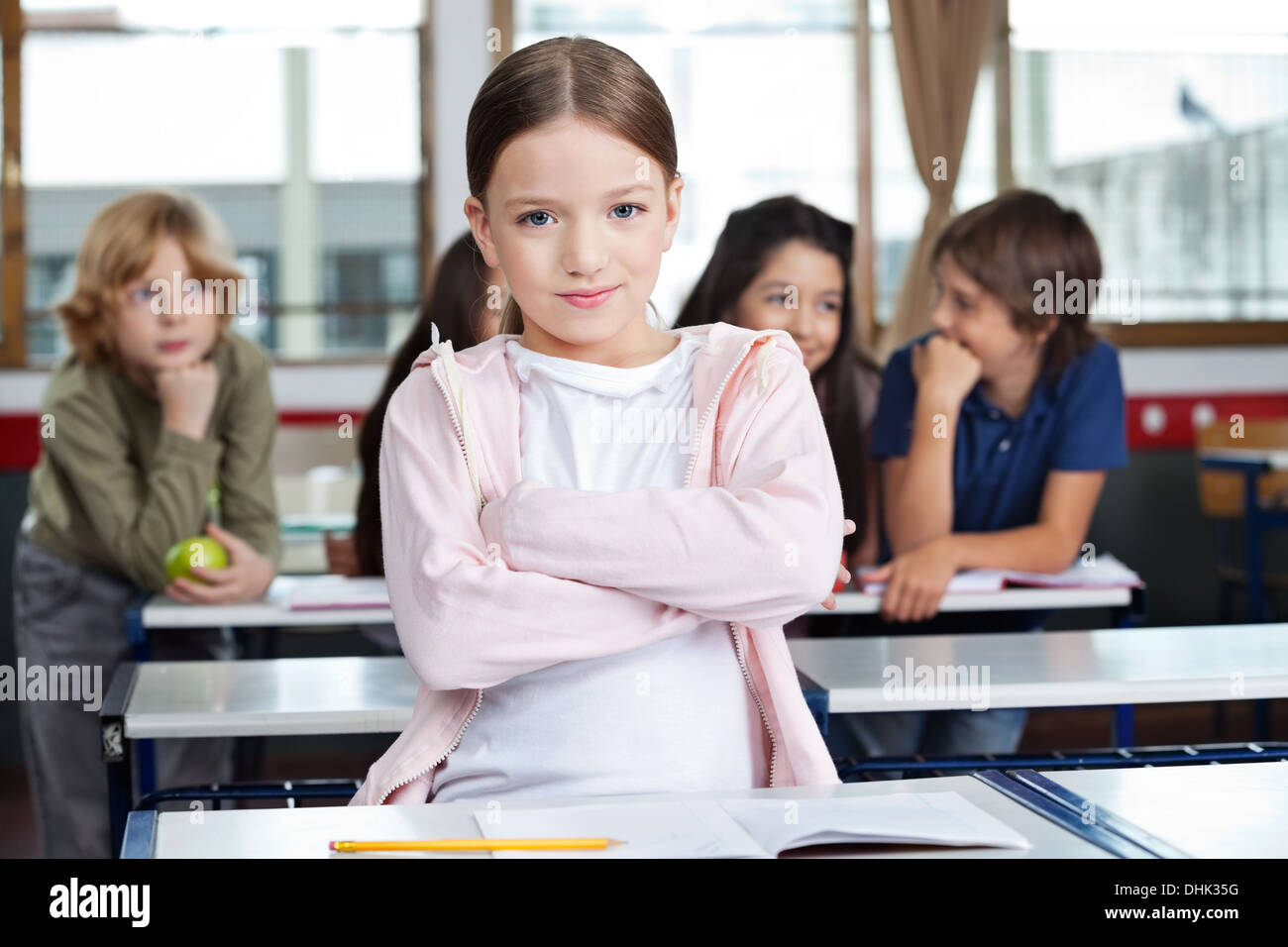 Schoolgirl Standing Arms Crossed In Classroom Stock Photo - Alamy