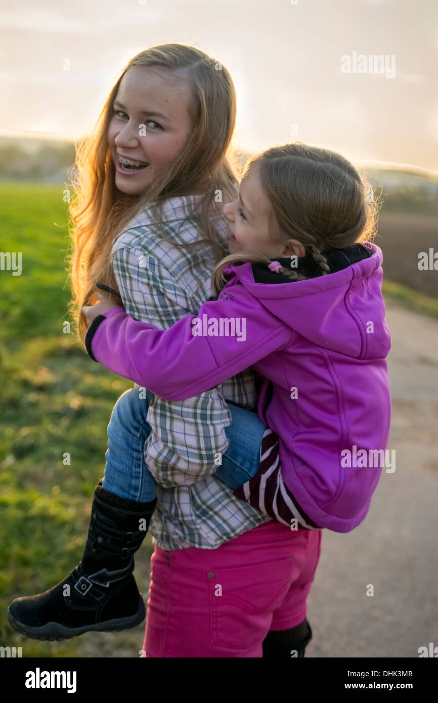 Teenage girl carrying girl piggyback Stock Photo - Alamy