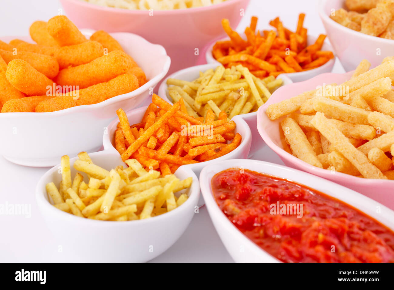 Potato, corn and wheat chips in bowls and red sauce isolated on gray ...