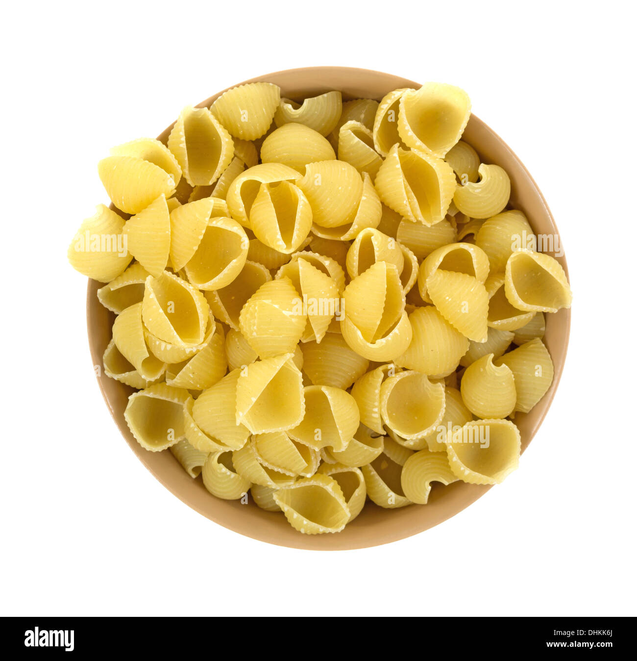 Top view of a tan bowl filled with small pasta shells on a white ...