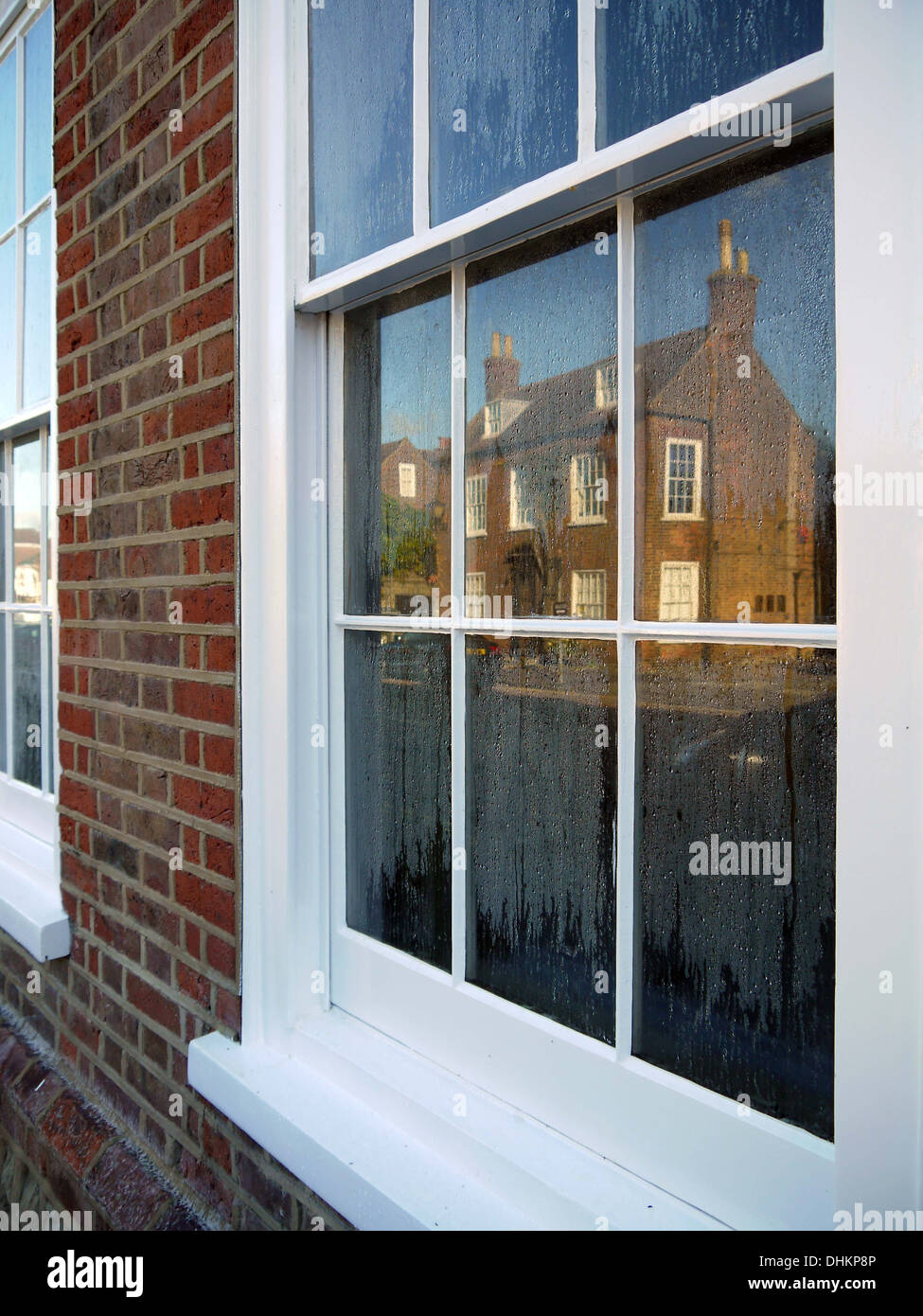 An English Country house is seen through the reflection of an old sash ...