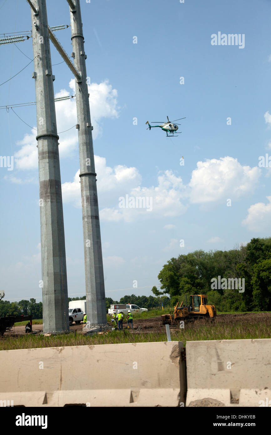 Helicopter stringing high tension electric wires between tall towers ...