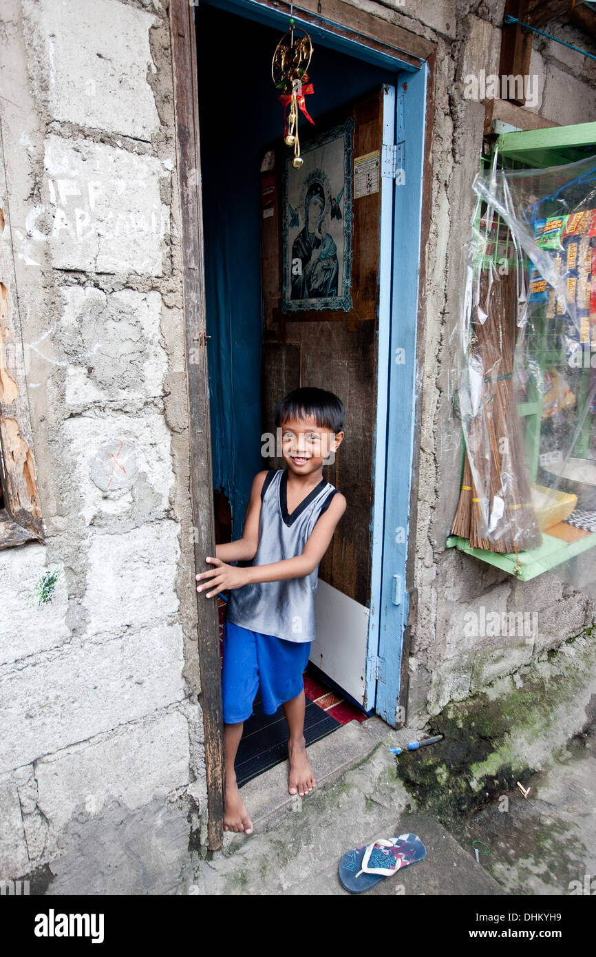 A young boy smiles at the camera from the door of his home in Manila ...